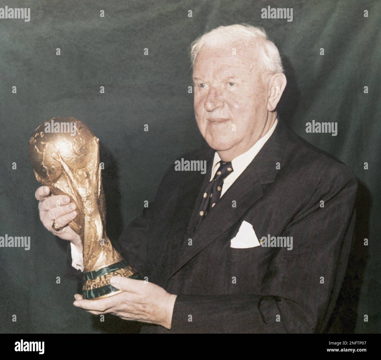 Sir Stanley Rous, President of FIFA, poses in London with a replica of ...