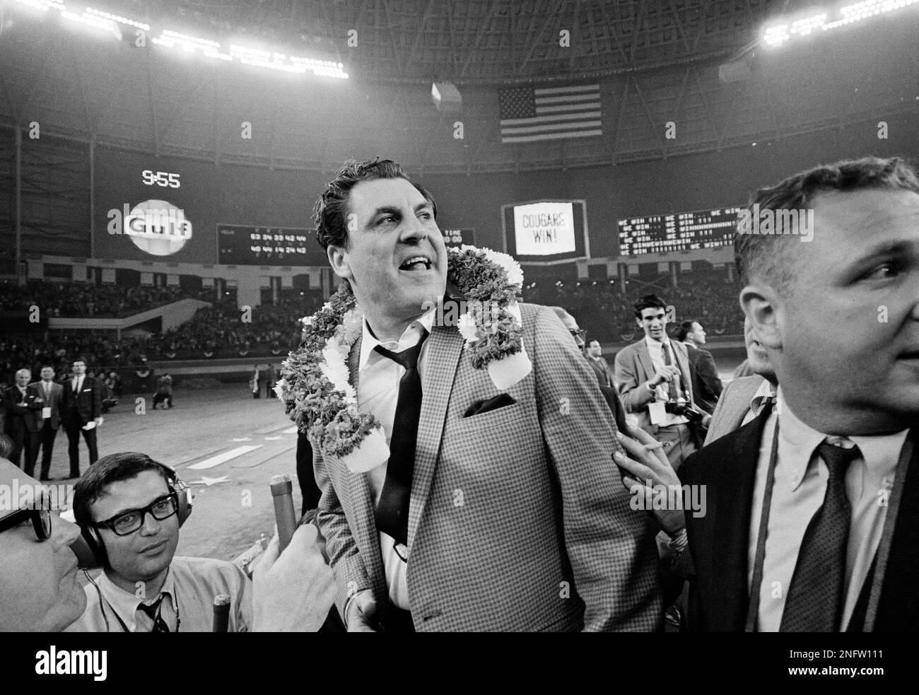 Guy V. Lewis, University of Houston basketball coach, wears a garland ...