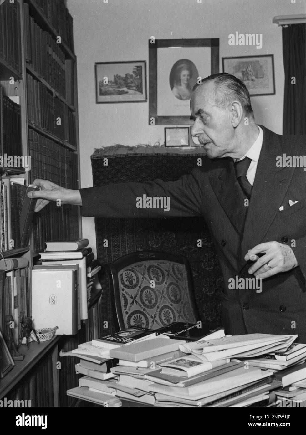 German dissident author, Thomas Mann stands in his study, taking a book ...