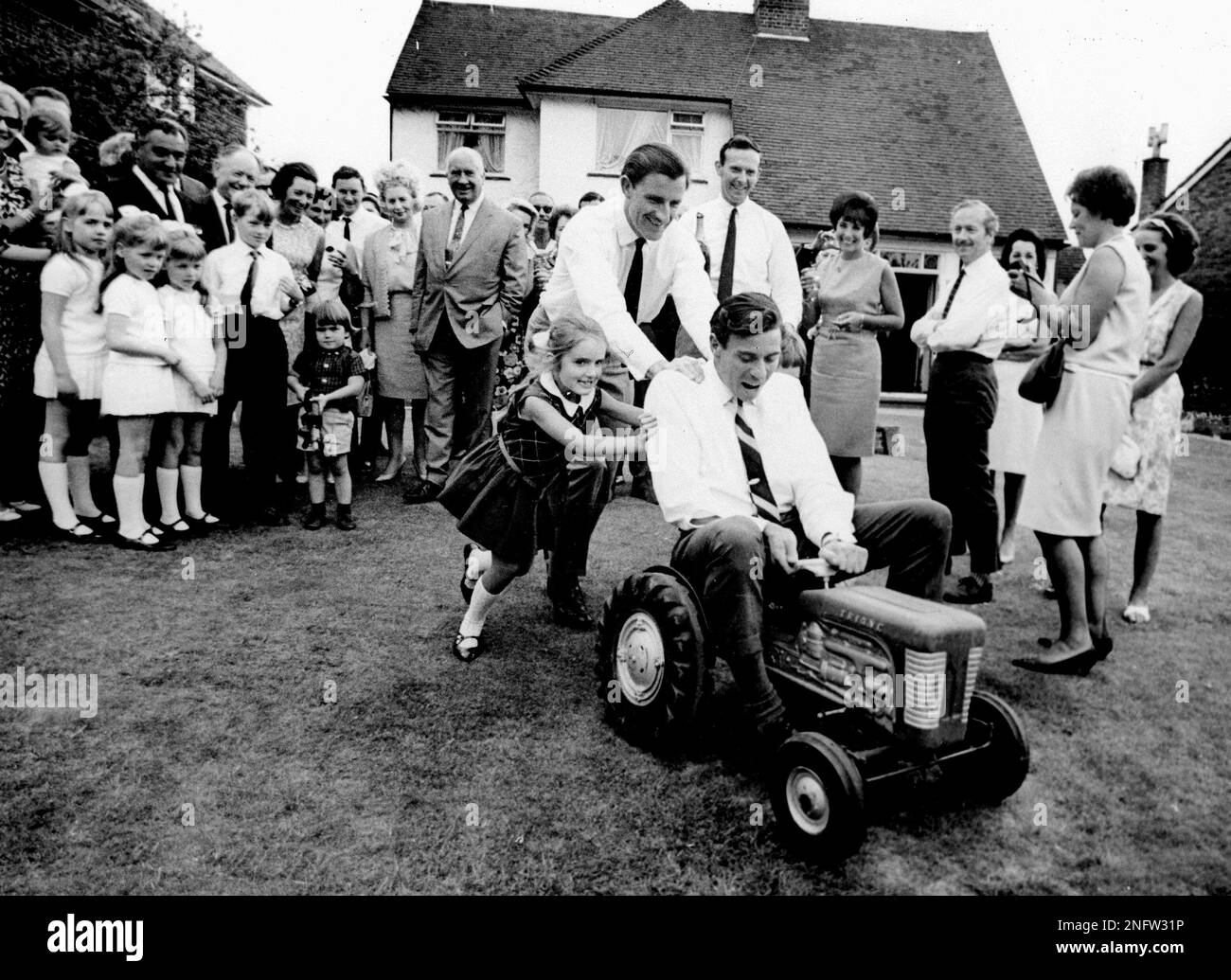 British auto racer Jim Clark gets a push on a pedal tractor from fellow ...