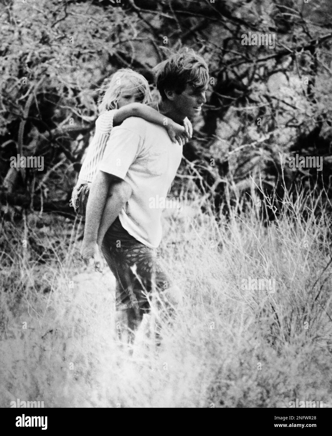 Robert F. Kennedy carries a little girl on his back. No other caption ...
