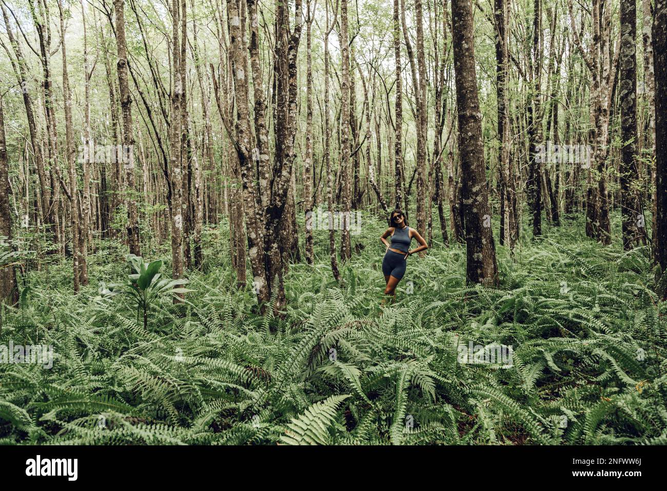 Beautiful young Latina girl in sportswear walks through the trees in ...