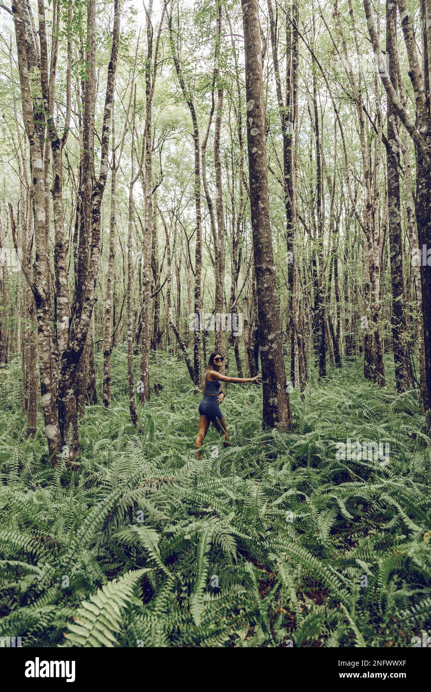 Beautiful young Latina girl in sportswear walks through the trees in ...