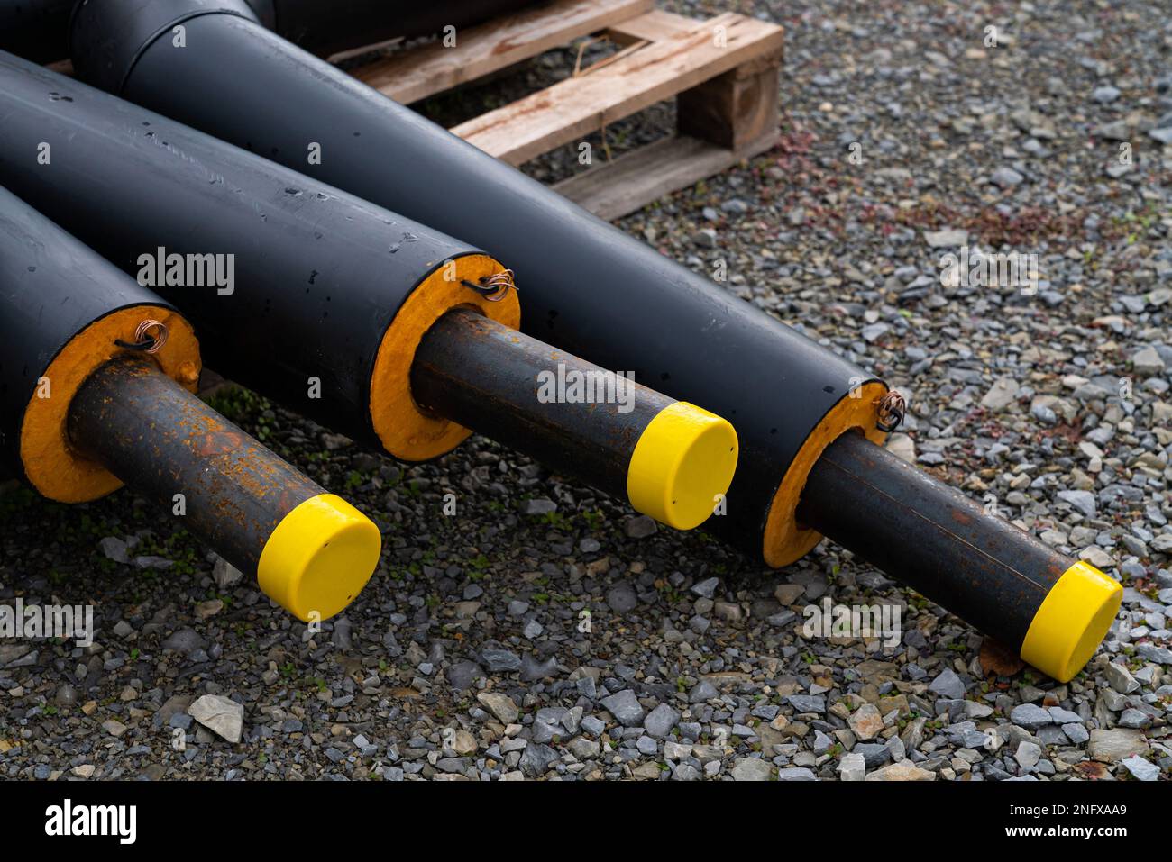 Black metal pipes in isolation lie on a construction site. Yellow ...