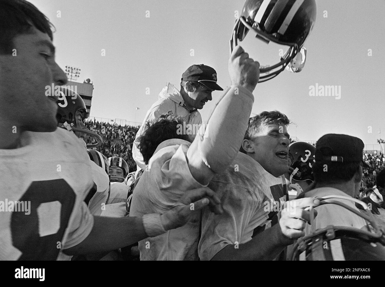 Missouri line backer lifts his helmet in a victory gesture as head coach Dan Devine is carried ...