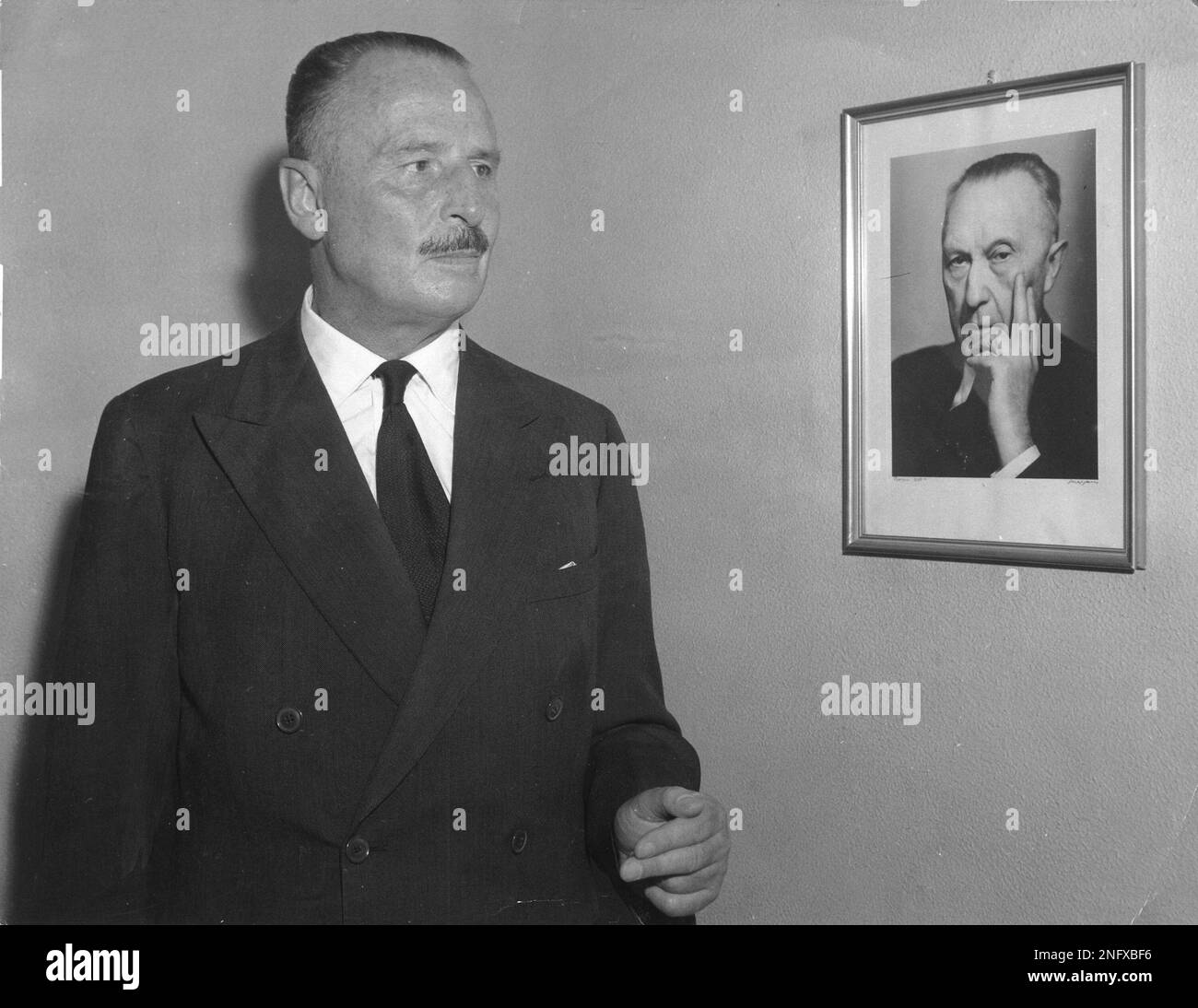Sir Oswald Mosley, leader of the Union Movement, poses next to a photo ...