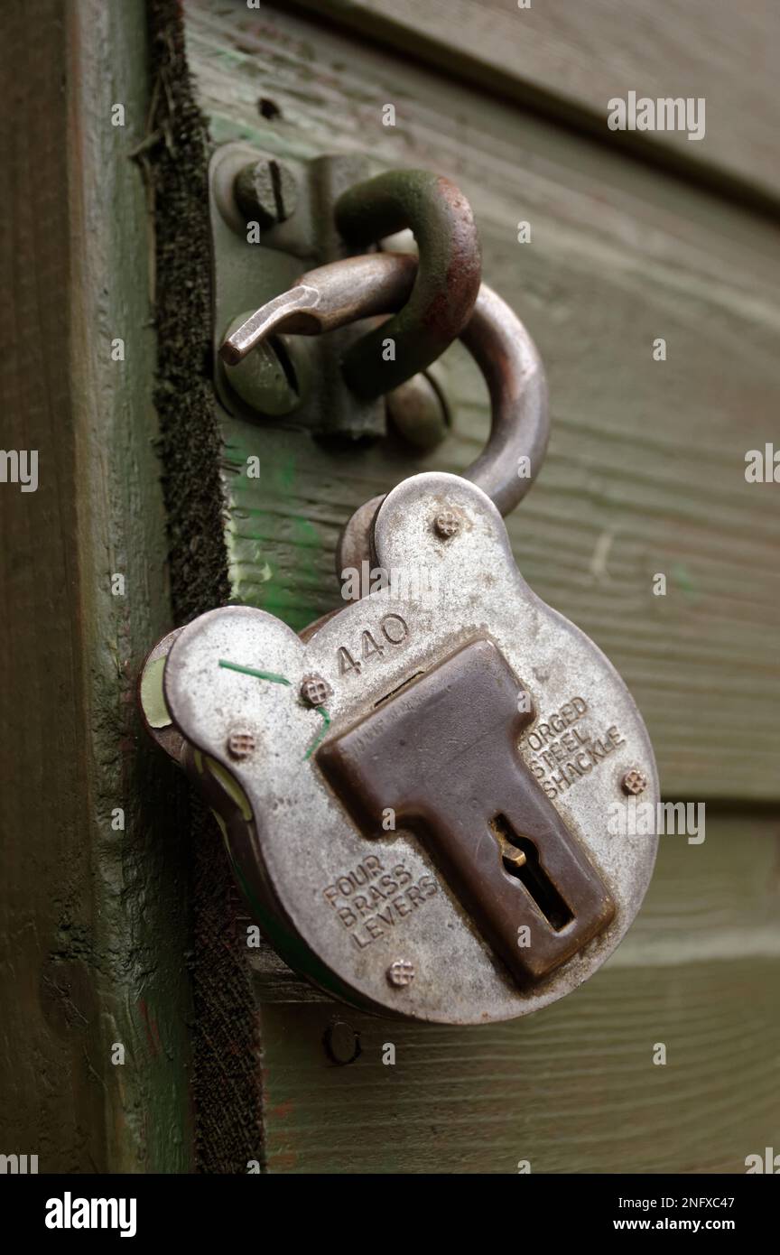 An old style padlock, unlocked and hanging on a garden shed. The shed ...