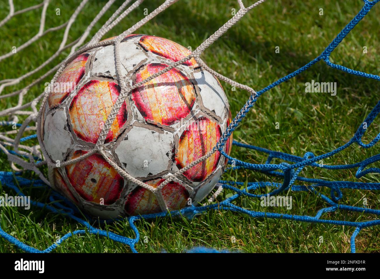 old soccer ball in the net on the background of grass soccer field ...