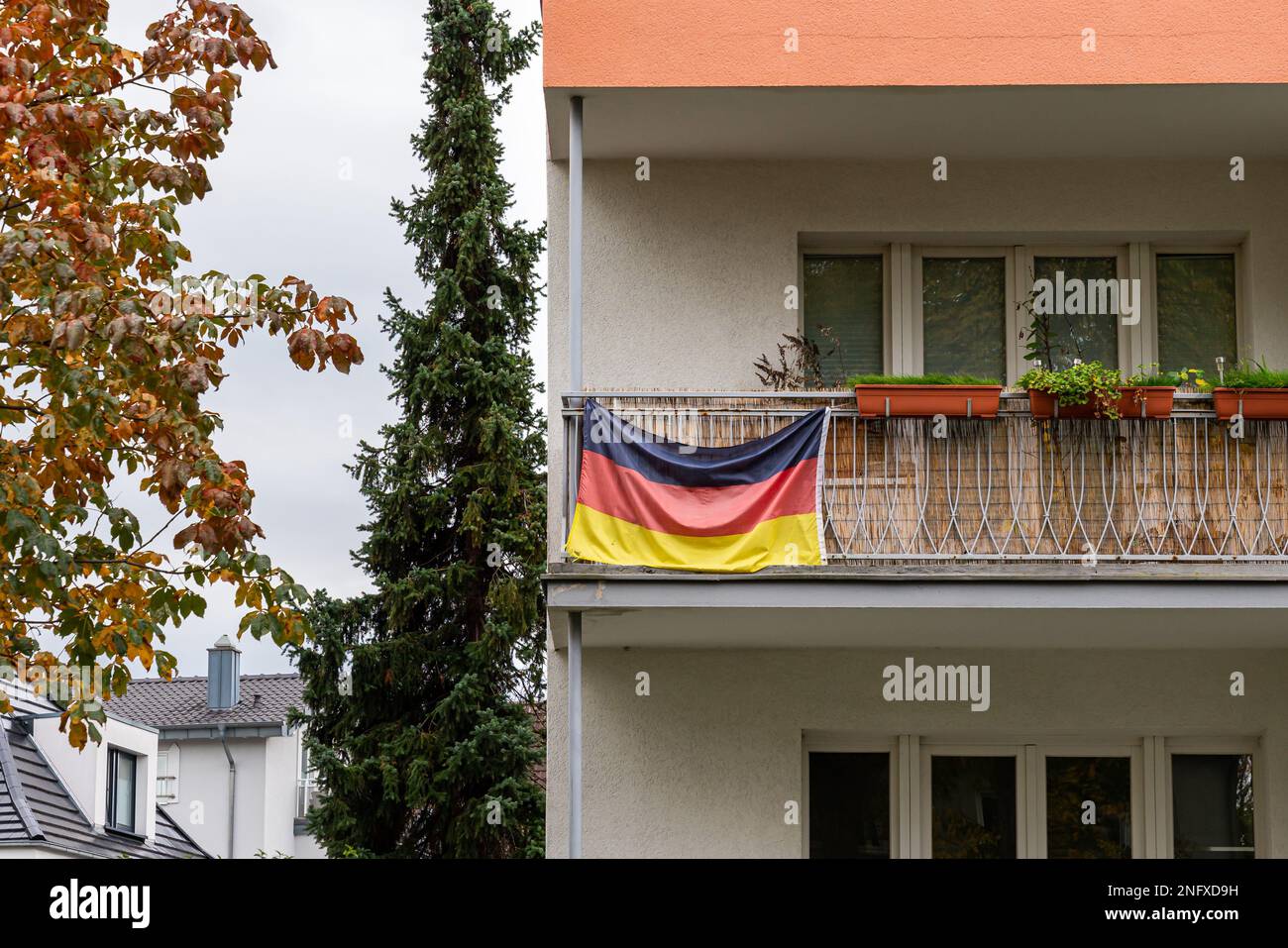 German flag hung on the balcony of an apartment building. Flower boxes ...