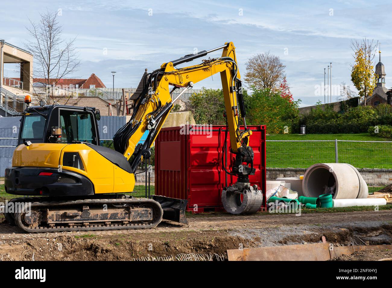 Yellow excavator and red metal container at the construction site ...