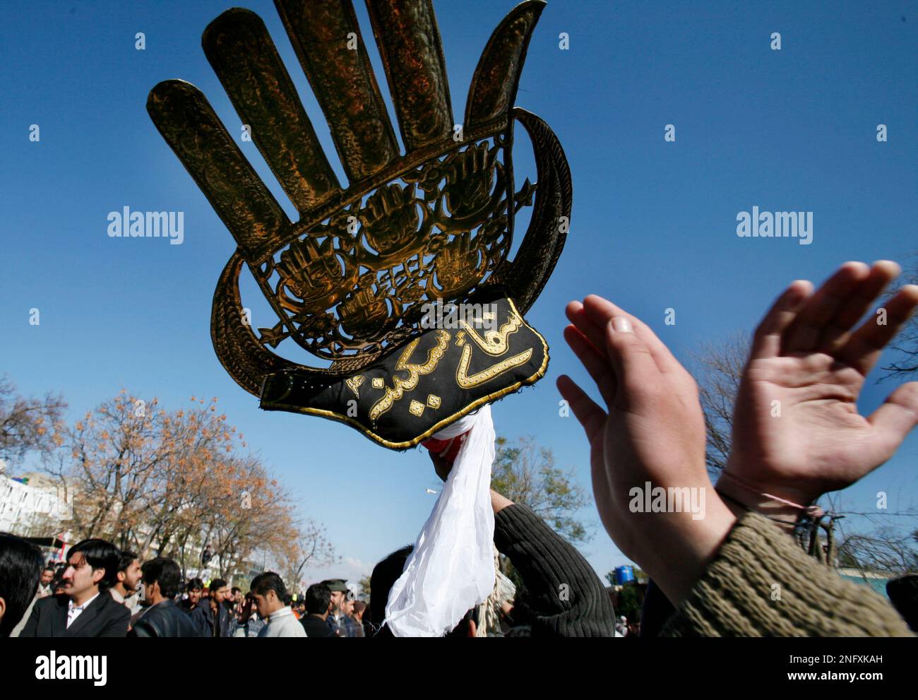 Pakistani Shia Muslims reach up to touch a religious symbol as part of ...