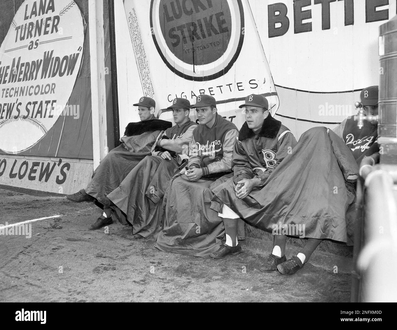 Brooklyn Dodgers teammates sit together by large billboards while ...