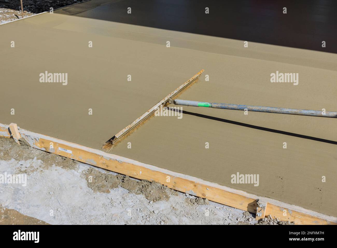 When construction worker uses broom to brush fresh wet concrete result ...