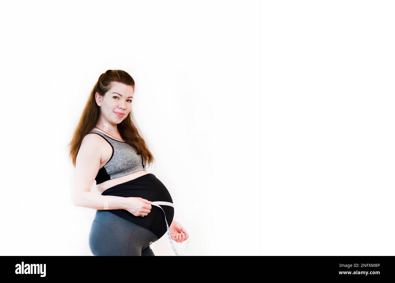 A Pregnant Woman With A Measuring Tape Measures Her Pregnant Belly