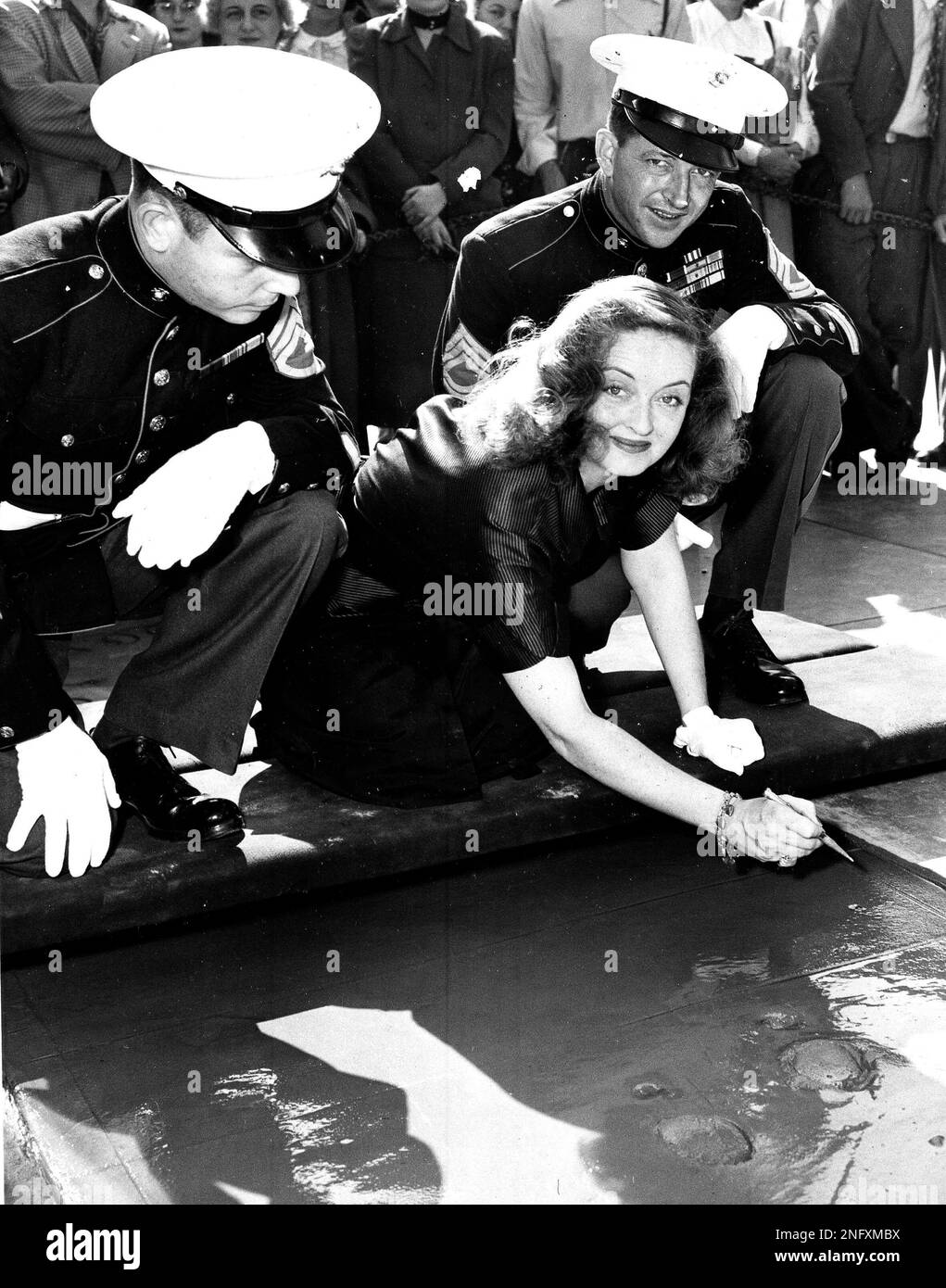 Actress Bette Davis places her signature in a cement square in the ...