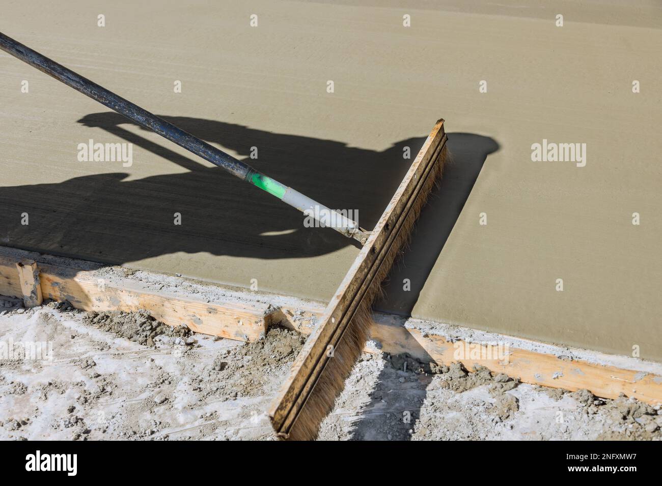Construction laborer use broom to brush fresh wet concrete causing ...
