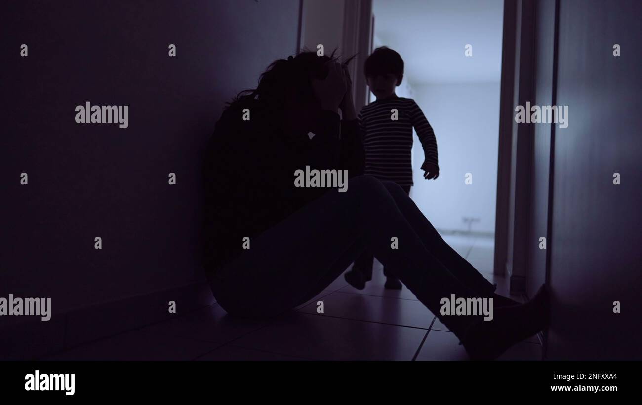Child hugging mother suffering at home floor. Little boy silhouette consoling parent during ...