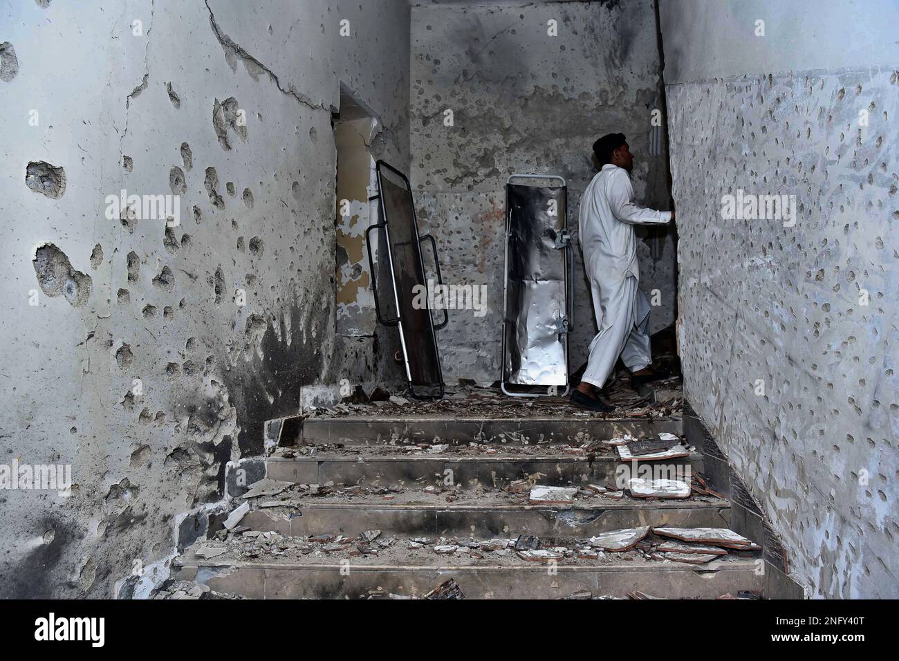 A plainclothes police officer stands beside the bullet-riddled walls ...