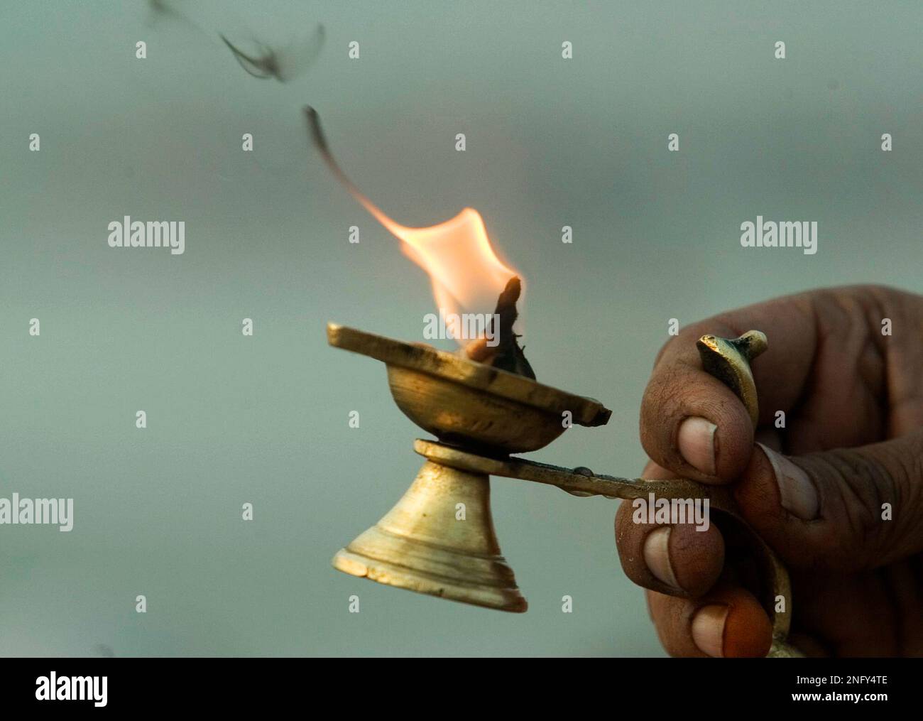 A Hindu devotee holds a traditional oil lamp as he offers prayers on ...