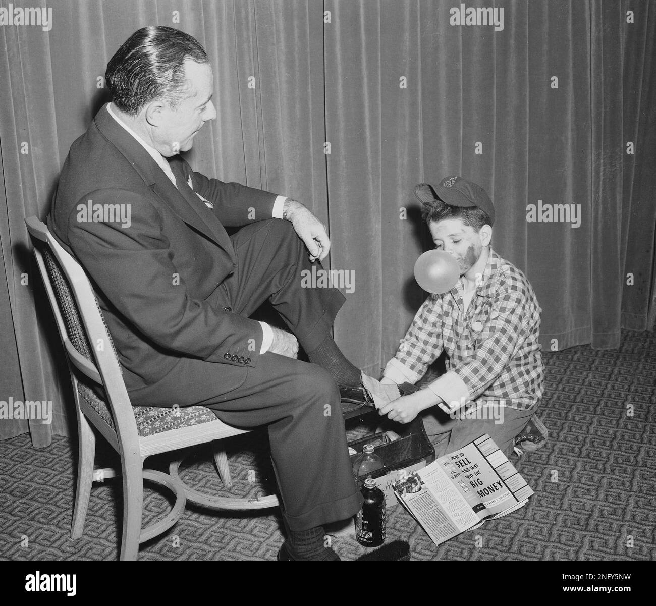 Raymond Duke a shoeshine boy, blows a bubble from his gum as he shines ...