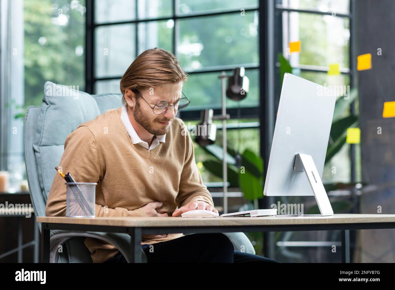 A young businessman, programmer, office worker sits at the table and ...
