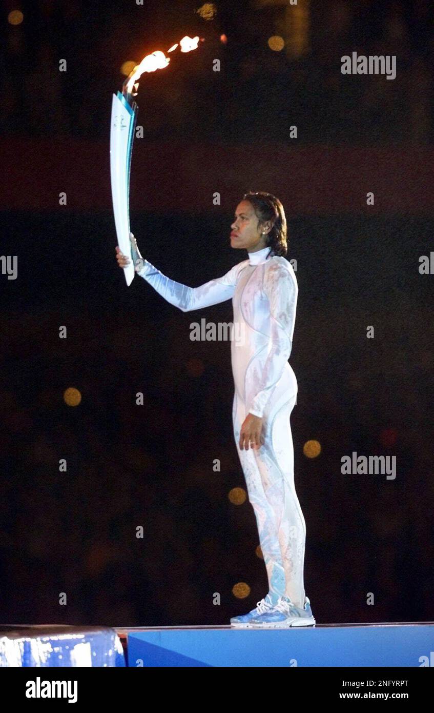 Australian Olympic athlete Cathy Freeman holds the Olympic torch aloft ...