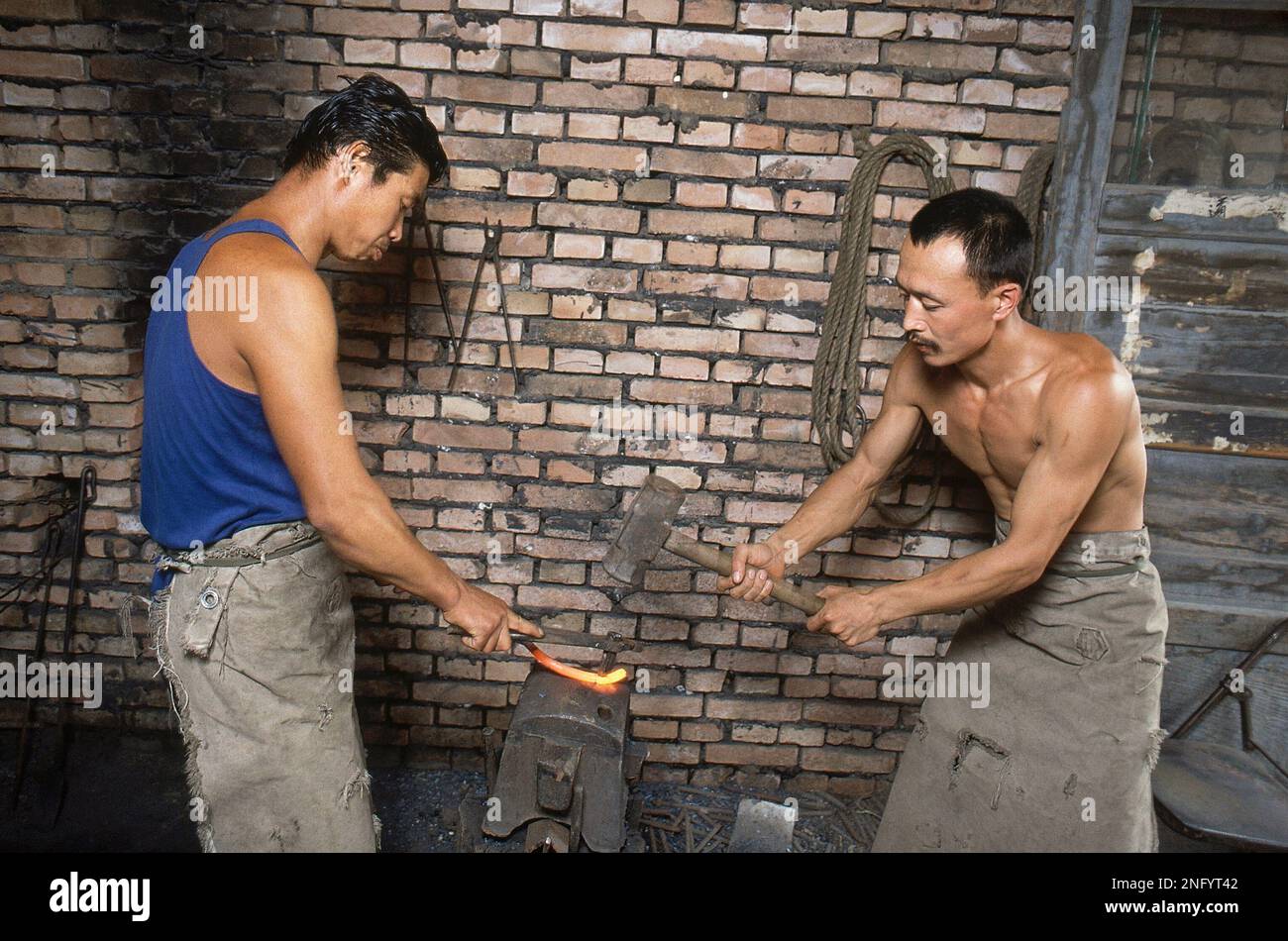 Chinese blacksmiths Yao Yuyin, left and Yao Changyuan hammer a ...