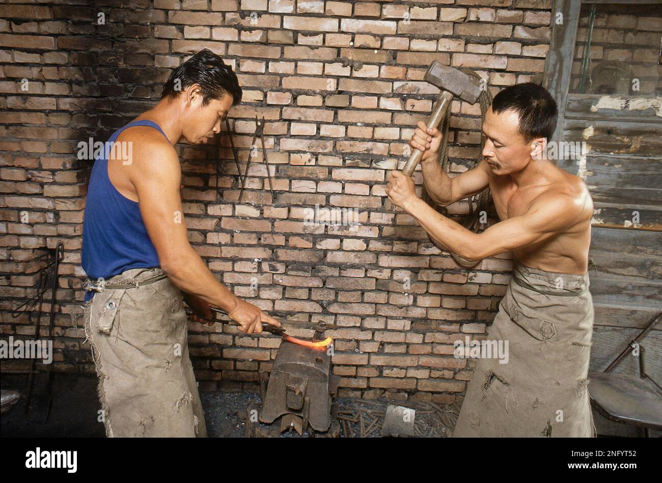 Chinese blacksmiths Yao Yuyin, left and Yao Changyuan hammer a ...