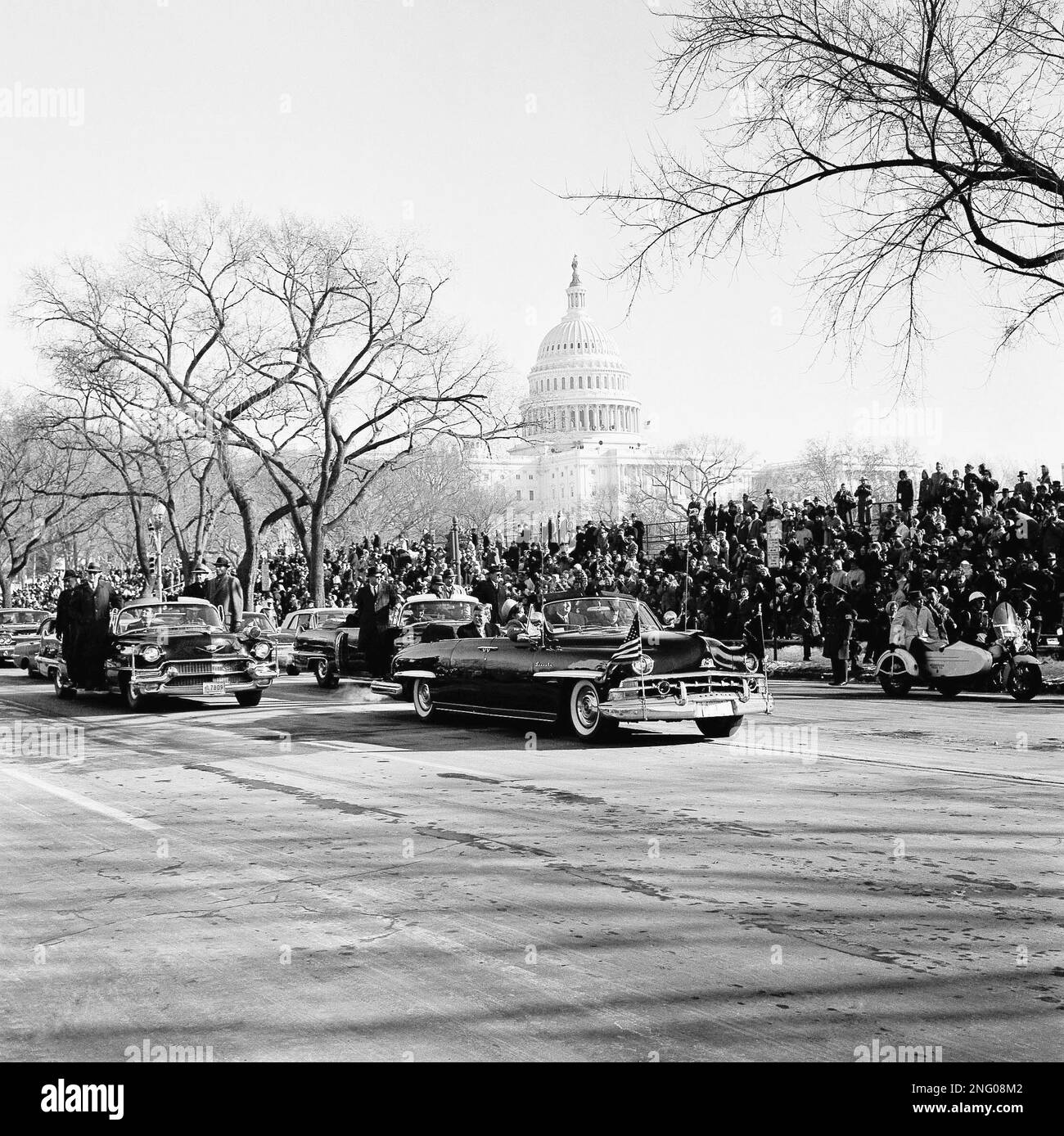 President John F. Kennedy and his wife Jacqueline sit in rear seat of ...