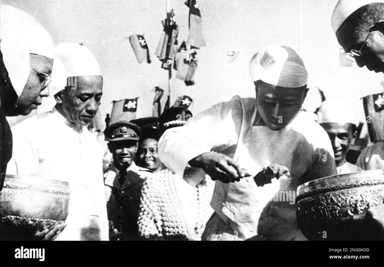 Burmese Prime Minister Thakin Nu applies cement to the base of the ...