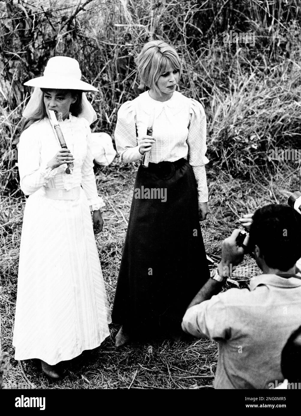 French actress Jeanne Moreau, left, and Brigitte Bardot eat sugar cane ...
