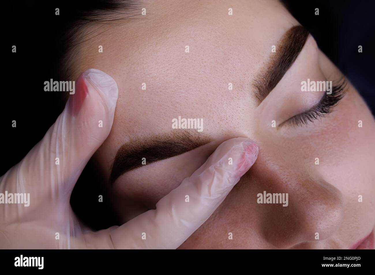 Permanent makeup of the eyebrows, the fingers of the master stretch the ...