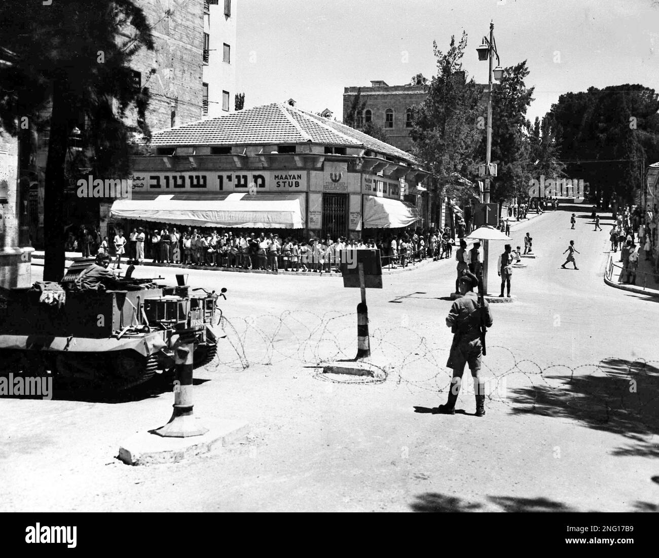 Armed troops and a bren-gun carrier, with barbed wire stretched across ...
