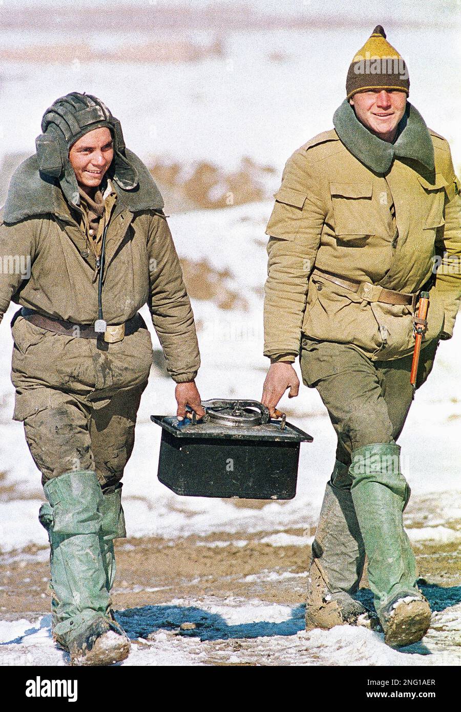 Two Soviet soldiers of an armored unit lift a battery in snow covered ...