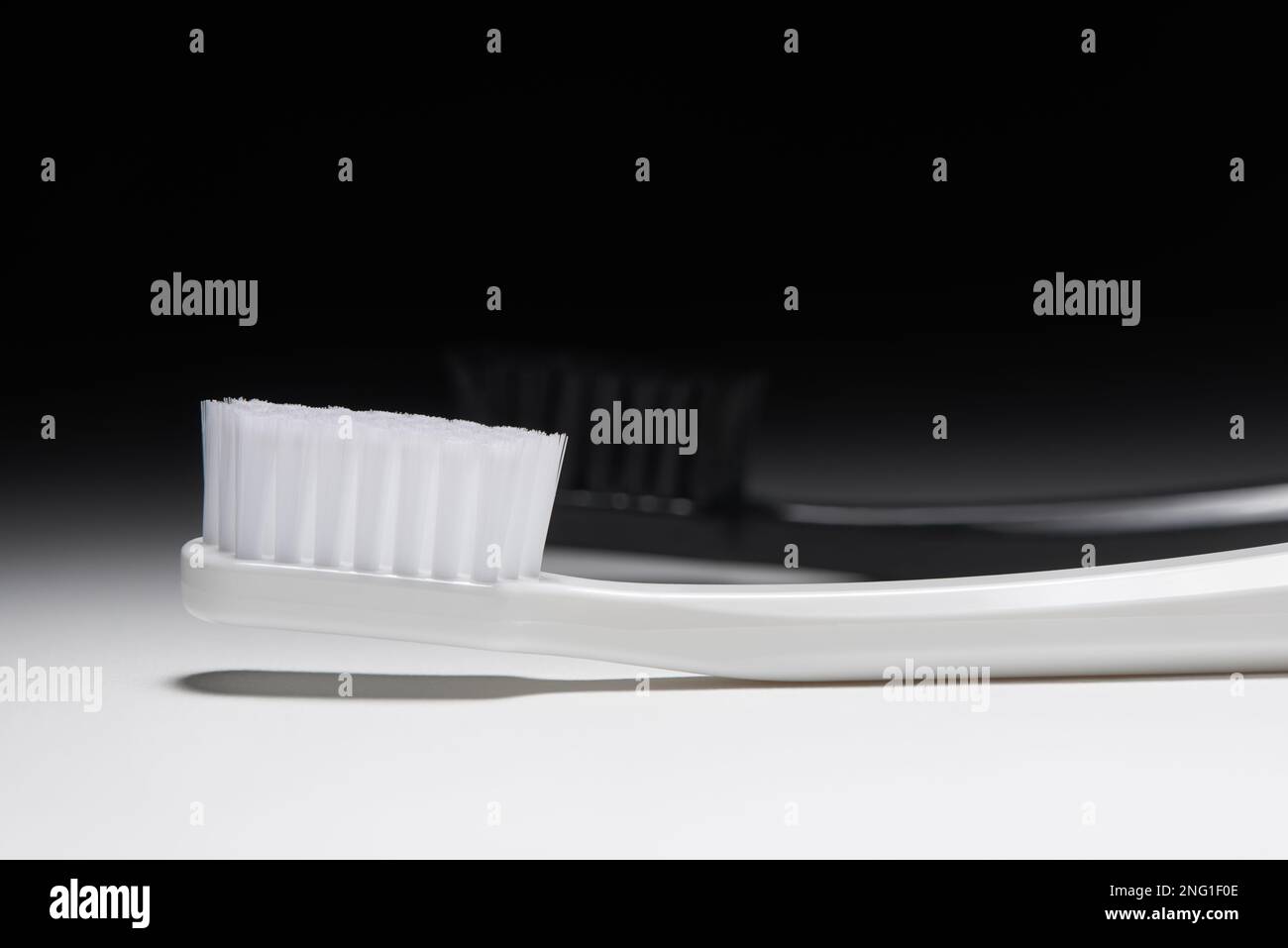White and black toothbrushes next to each other on dramatic background ...