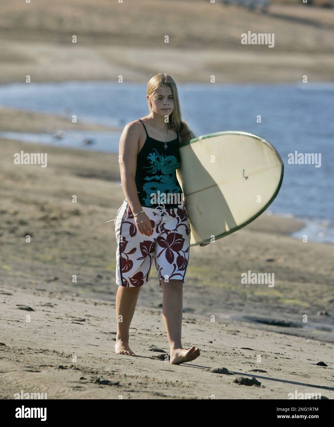 Claire Carlson, 17, carries her long board along a beach in San Diego ...