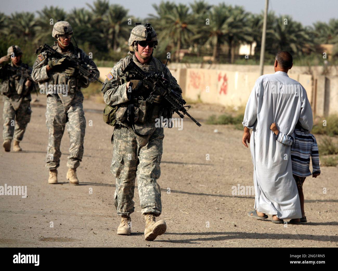 An Iraqi boy clutches his father's garment as they watch U.S. Army ...