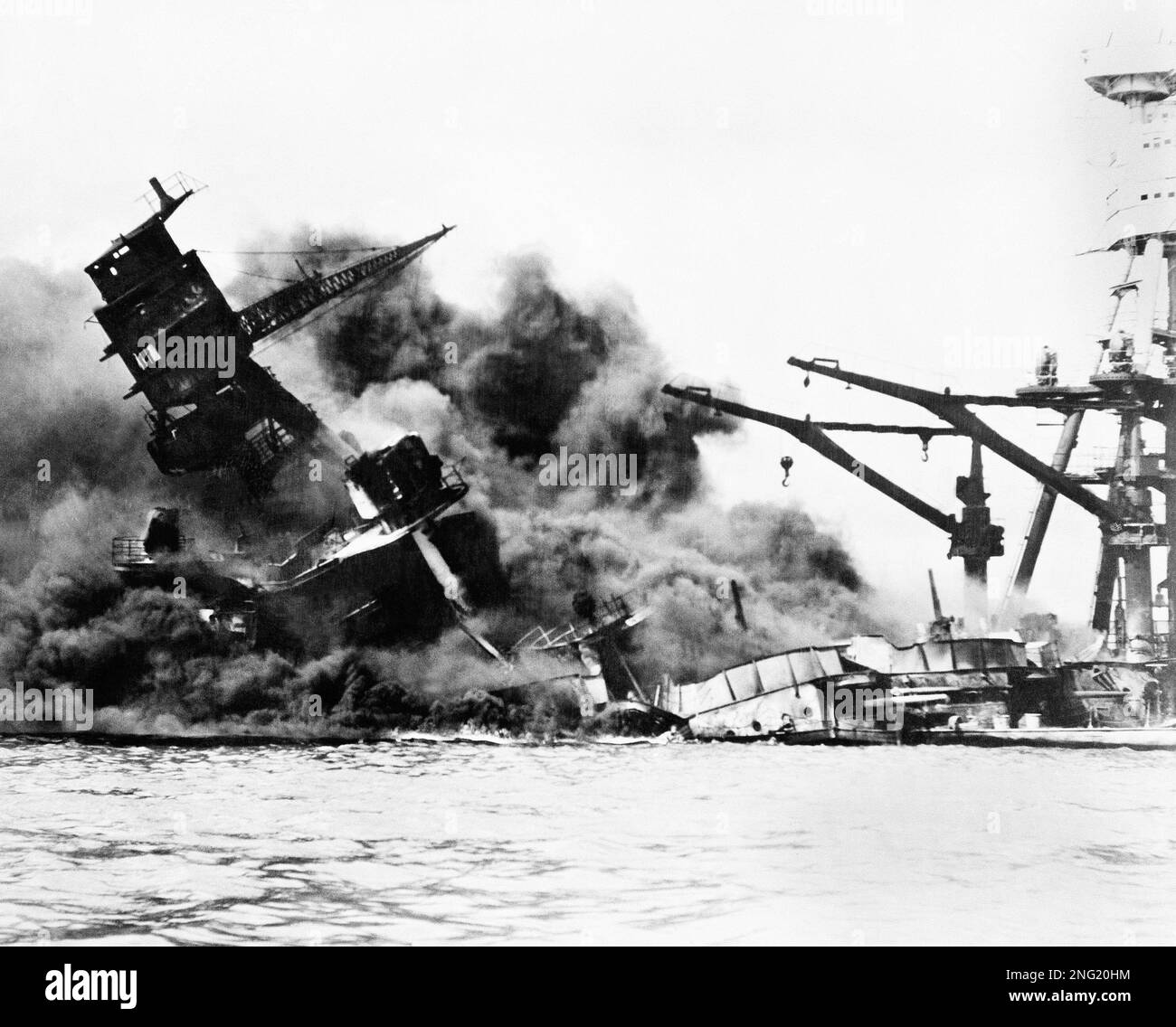 The battleship USS Arizona belches smoke as it topples over into the ...