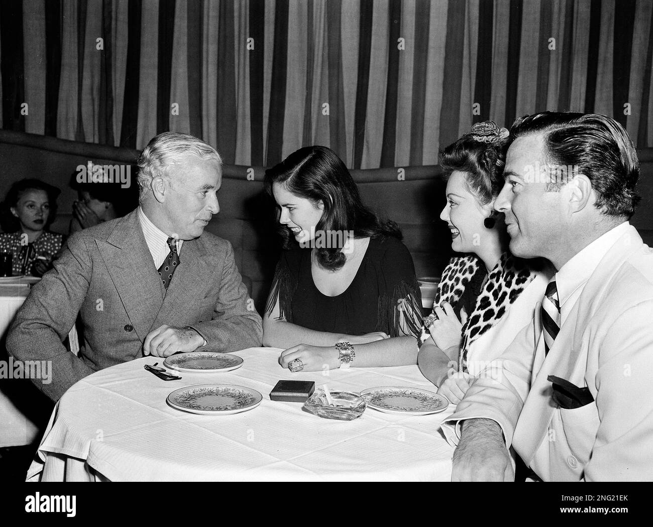 Actor Charlie Chaplin sits with his wife Oona, and William Post and his ...