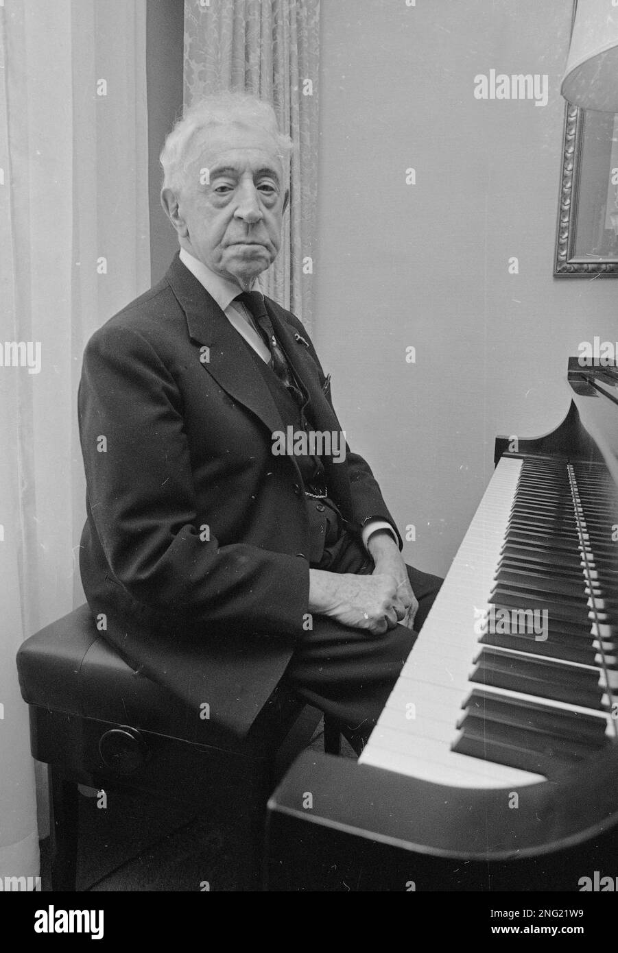 Pianist Arthur Rubinstein sits by the piano in his New York hotel suite ...