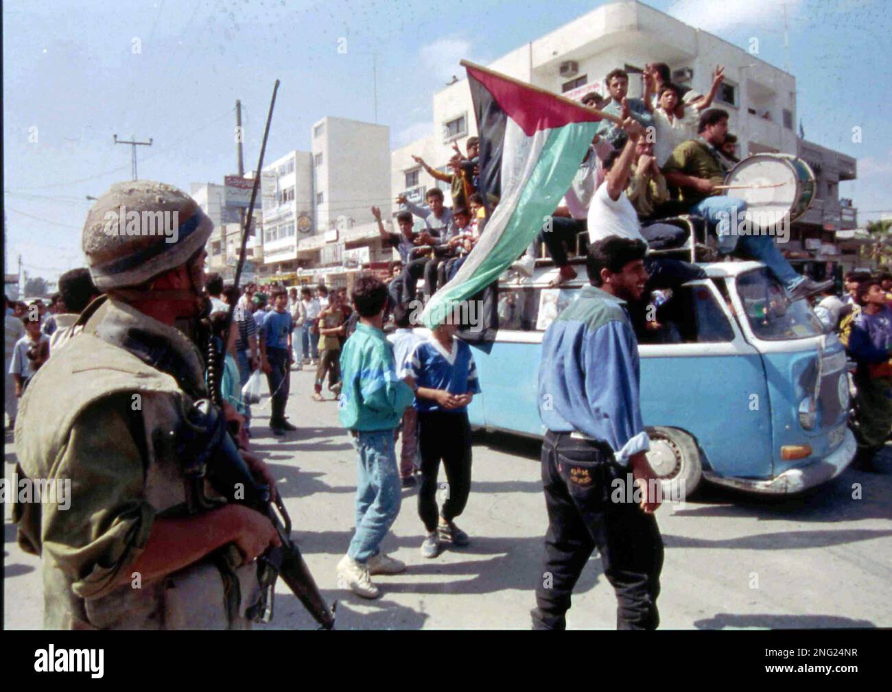 An Israeli soldier watches as jubilant Palestinians ride on a truck in ...