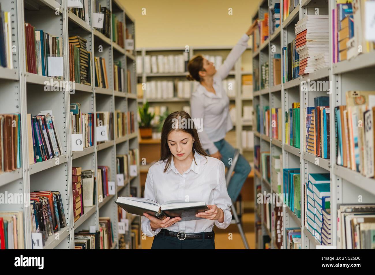 Two young female students in a public library Stock Photo - Alamy