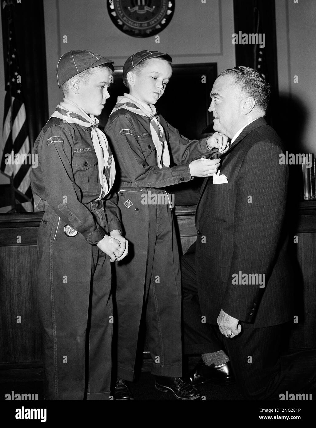 J. Edgar Hoover, head of the FBI, gets a Boy Scout badge from two ...