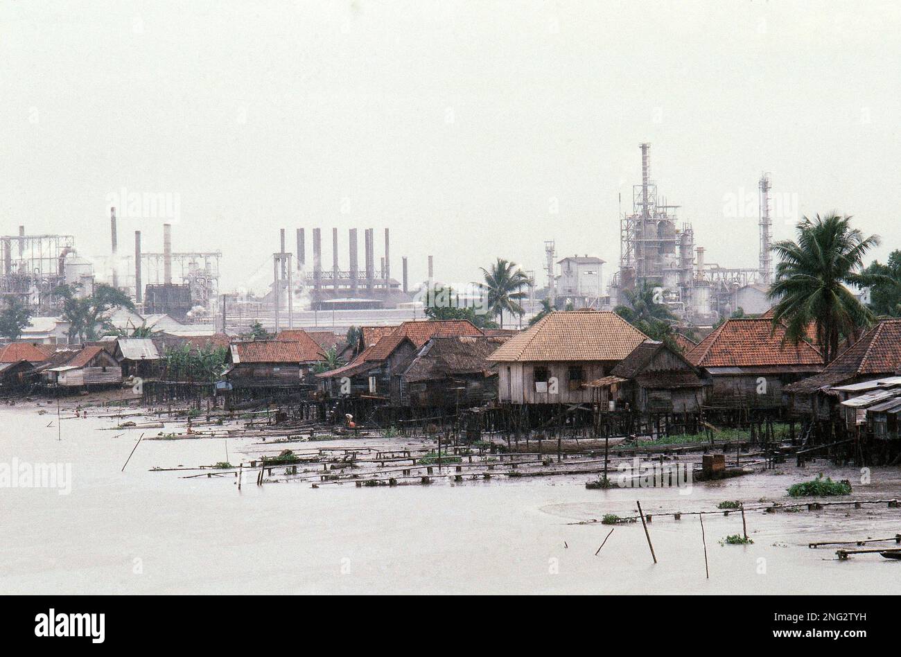 A scene of life in Sumatra with houses and a refinery in the background ...