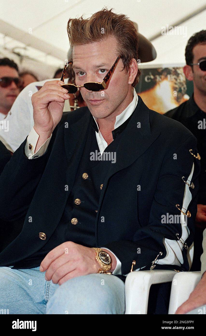 American actor Mickey Rourke peeks out at journalists from behind his ...