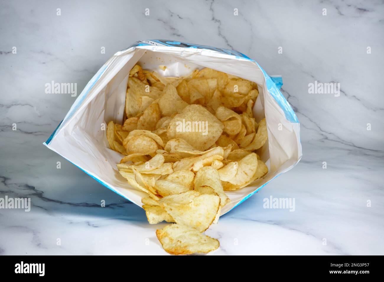 Bag of potato chips laying on counter with chip falling out Stock Photo ...