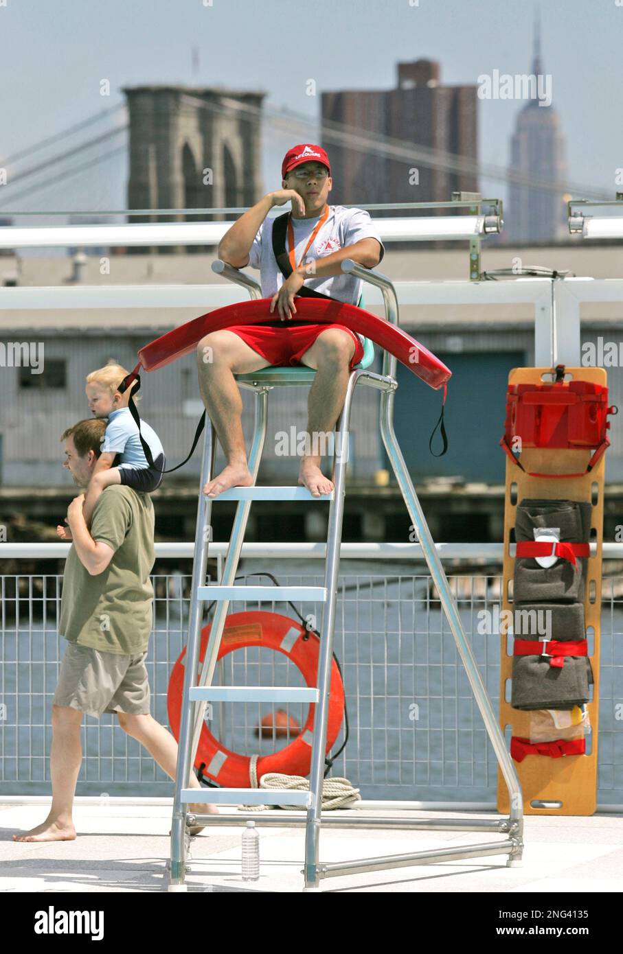A lifeguard keeps watch on the pool deck as the Brooklyn Bridge and the ...