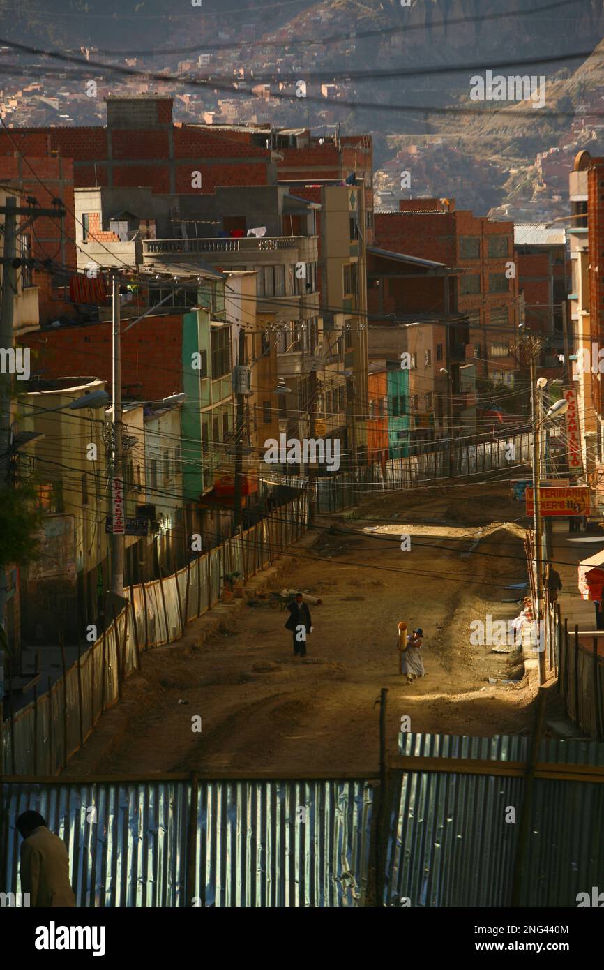 A Bolivian woman, right carries a water conduit while working on a ...