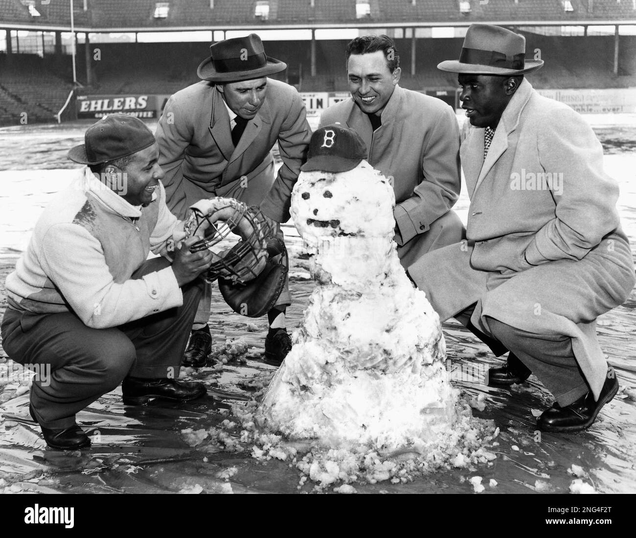 Members of the Brooklyn Dodgers gather around a snowman on the diamond ...