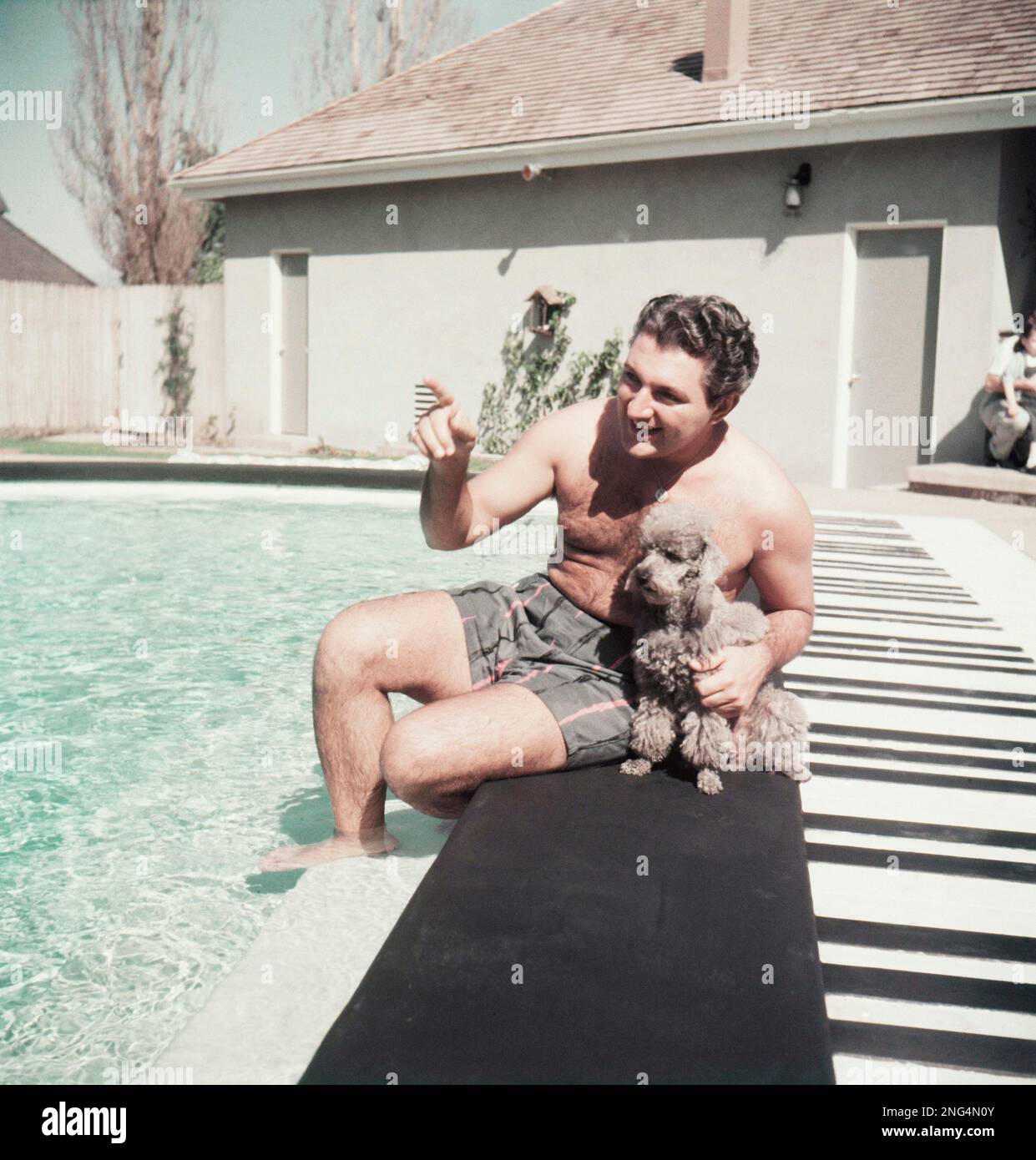 Entertainer Liberace sits by his pool with poodle dog at California ...